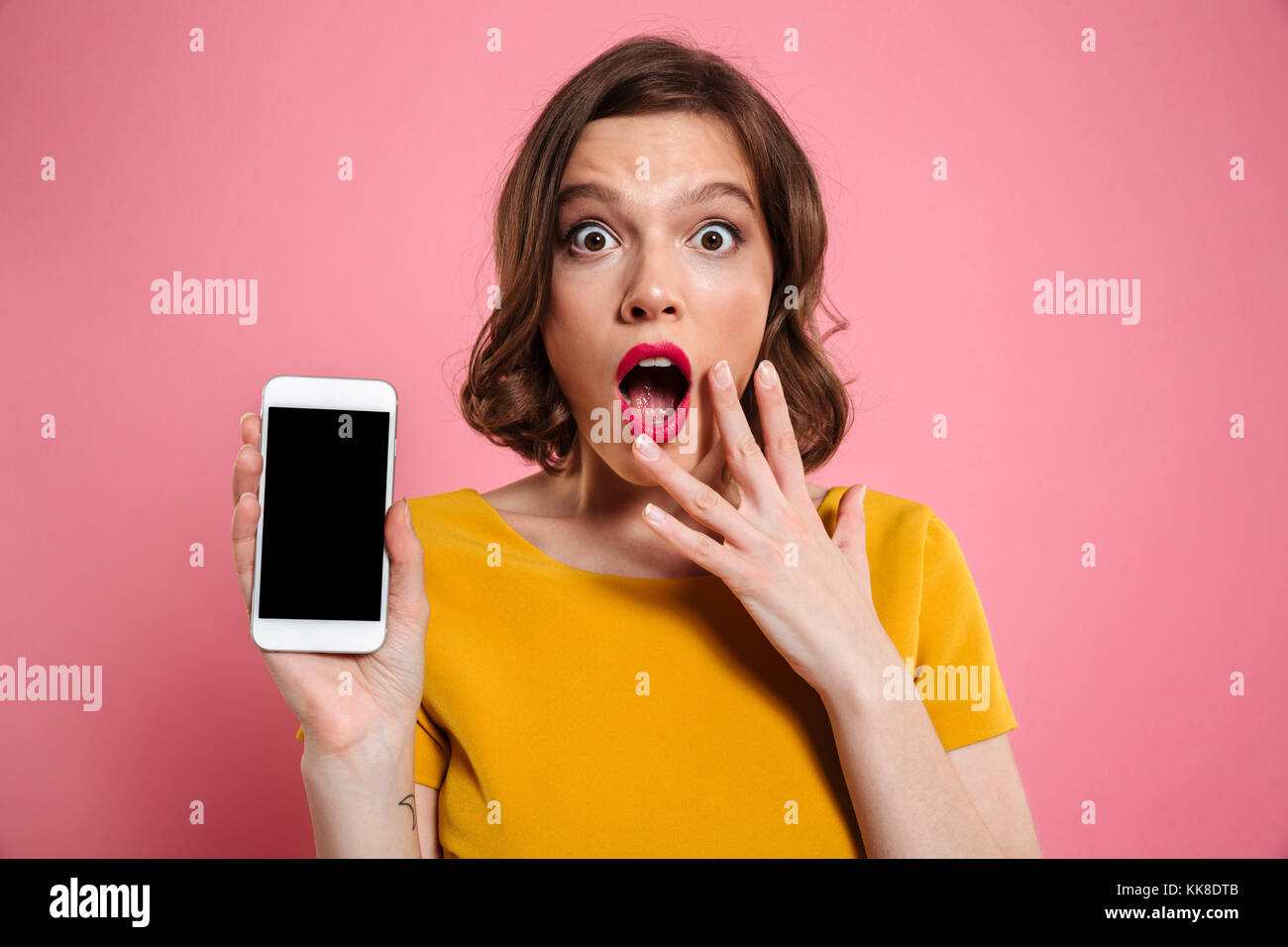 Close up portrait of a shocked young woman showing blank screen mobile ...
