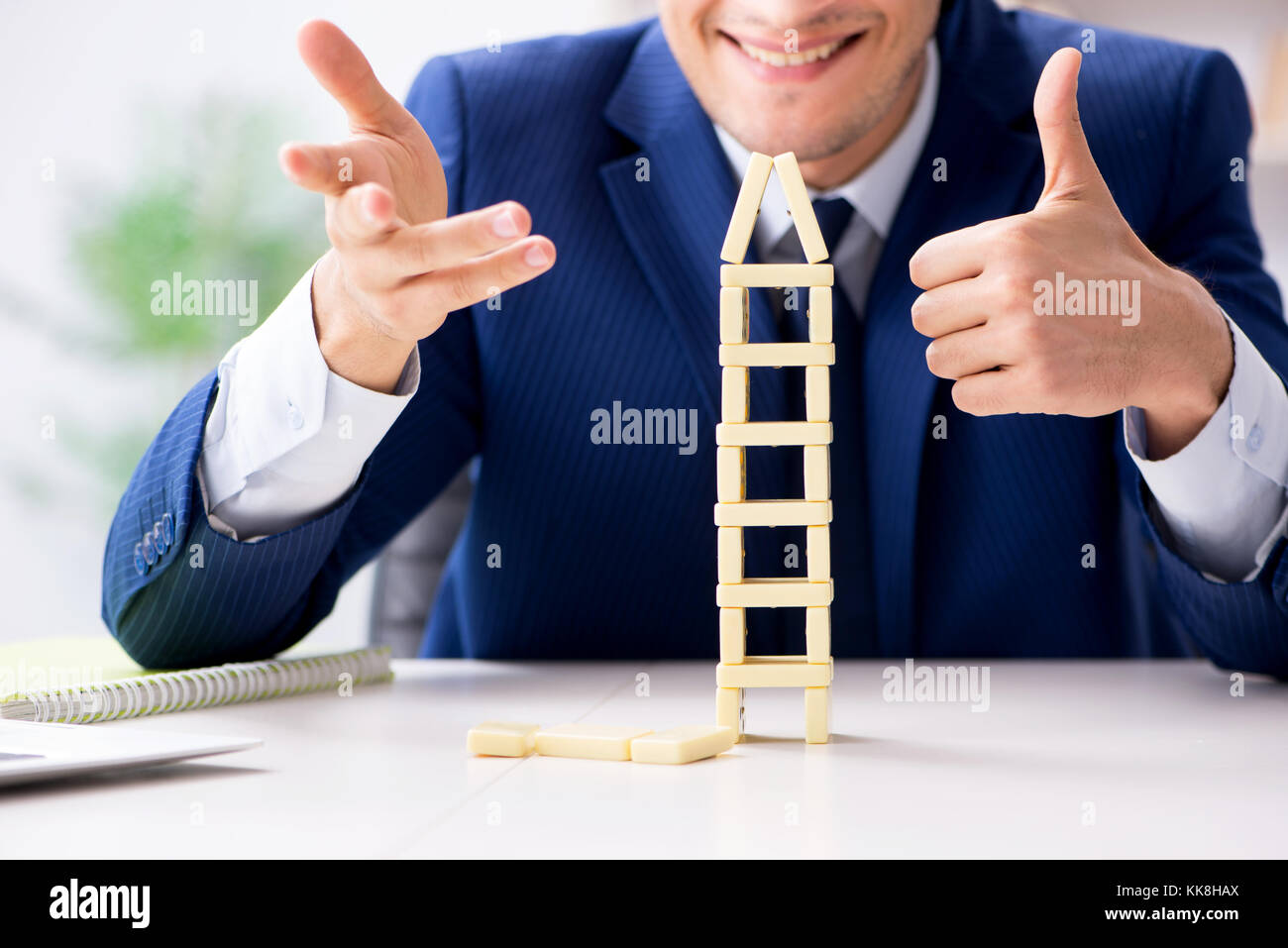 Young businessman building domino tower in office Stock Photo - Alamy