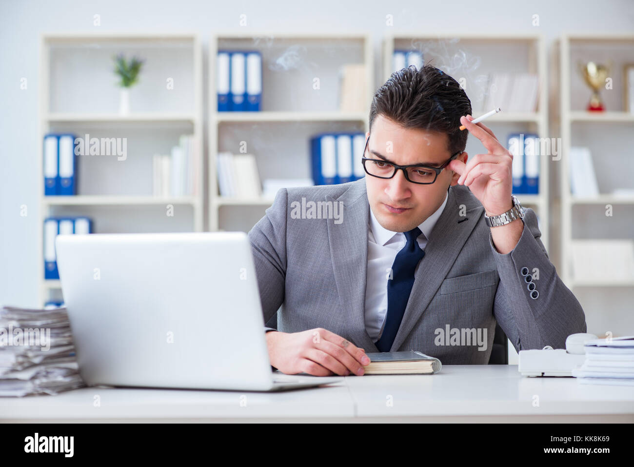 Businessman smoking in office at work Stock Photo - Alamy