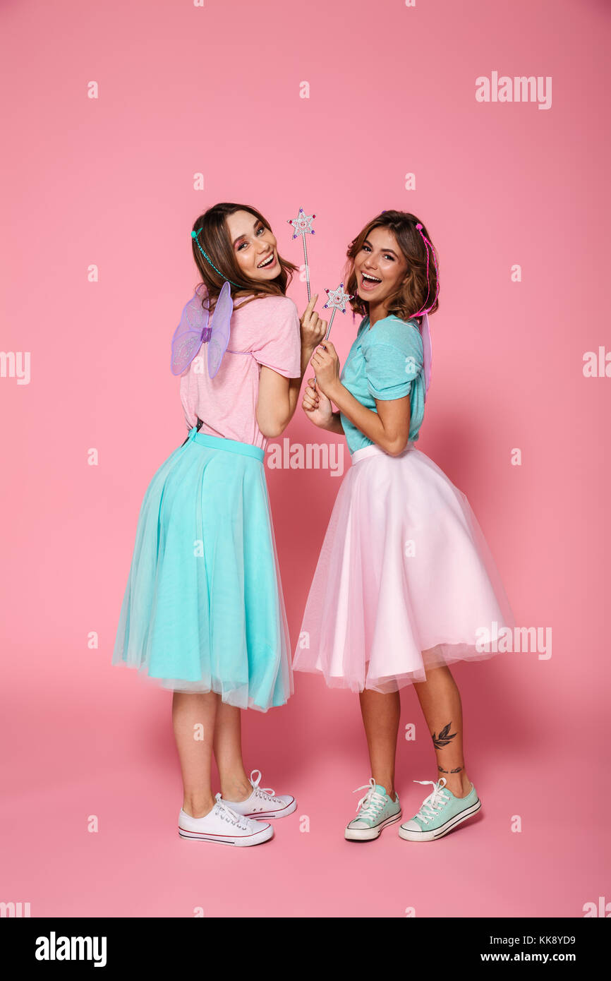 Full length side view portrait of a two joyful girls dressed like ...