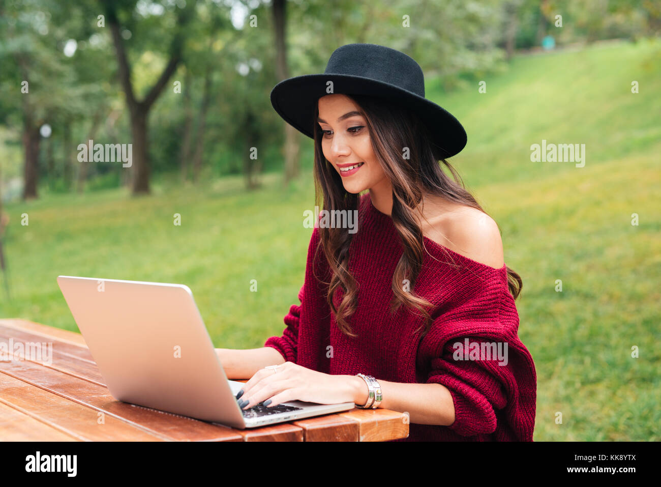 Portrait of a smiling pretty asian girl using laptop computer while ...