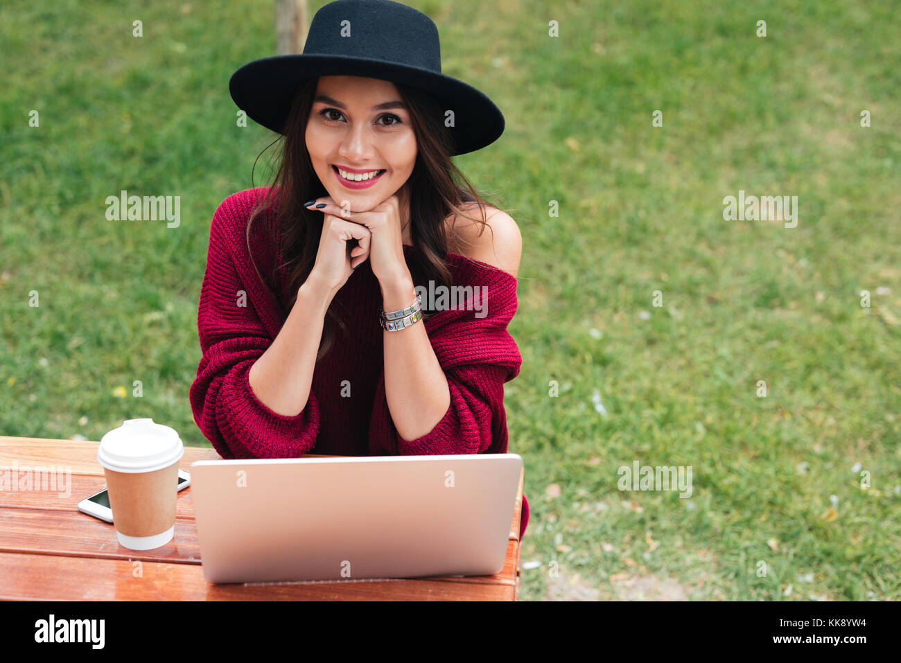 Portrait of a smiling pretty asian girl using laptop computer while ...