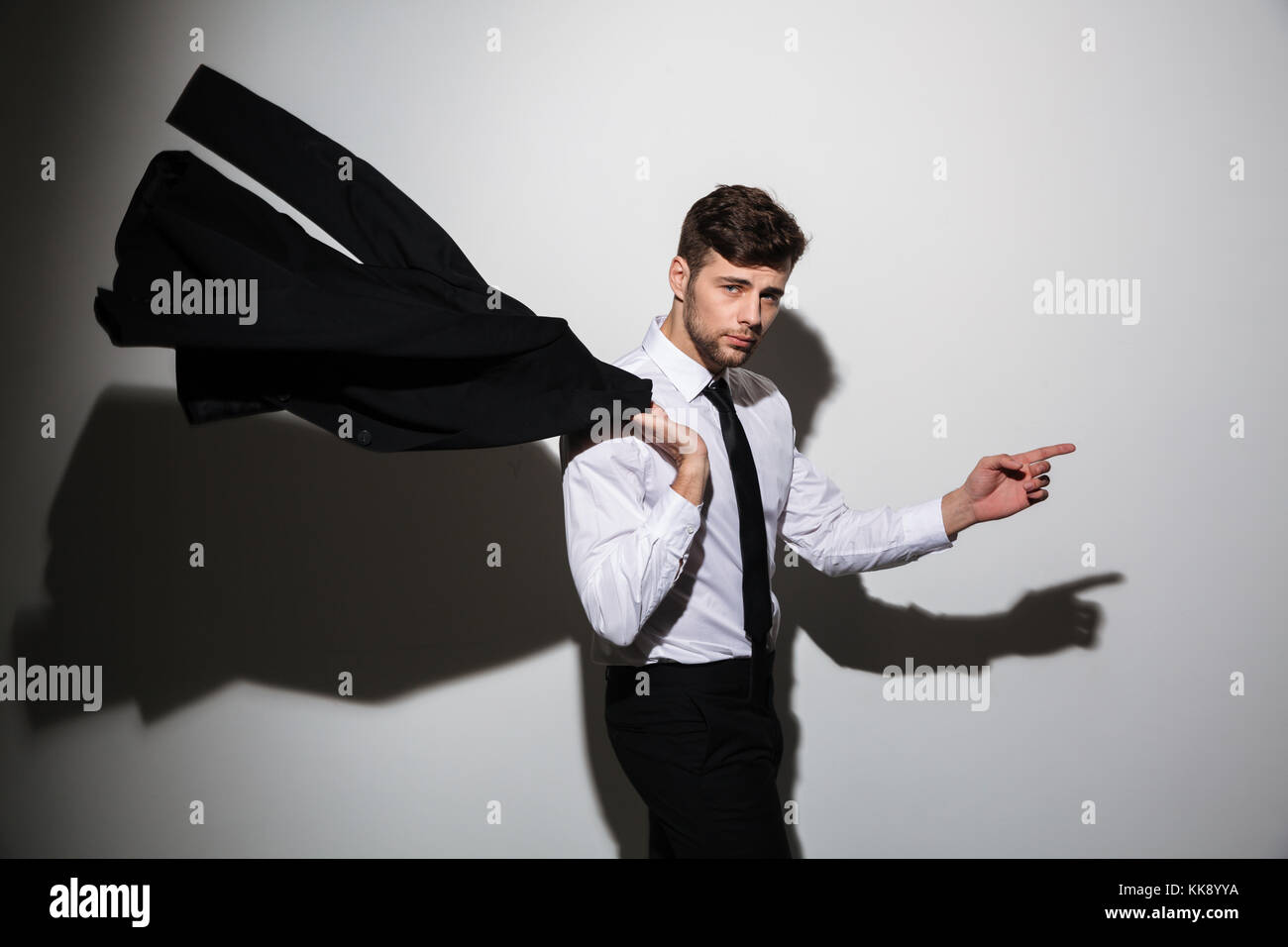 Portrait of a confident smiling man in suit posing while holding jacket ...