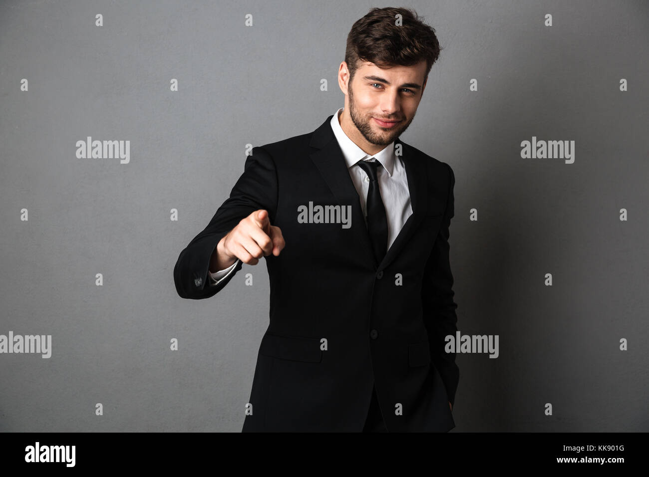 Young smiling man in formal wear pointing with finger on you, looking ...