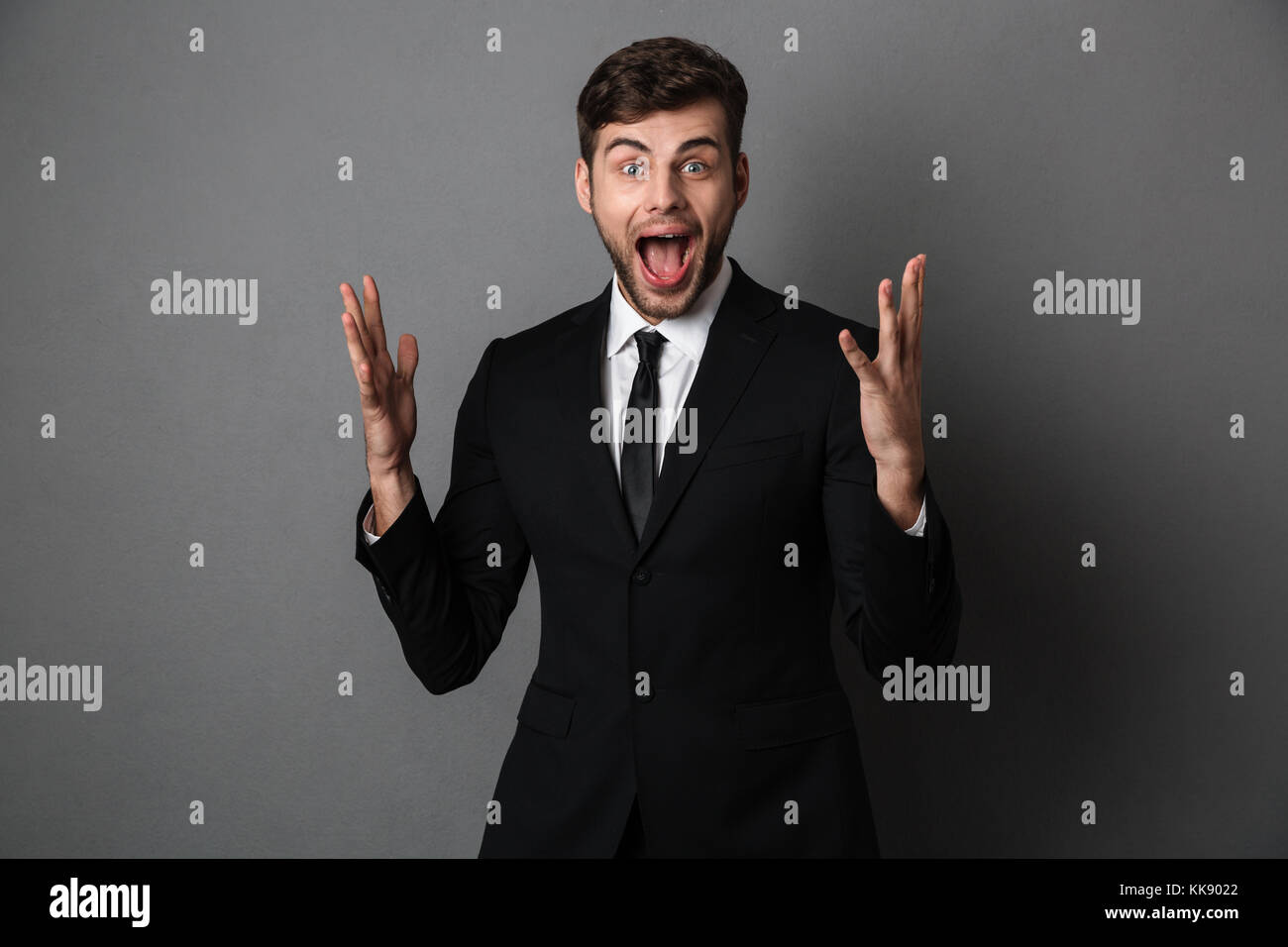 Young emotional screaming businessman standing with opened palms ...