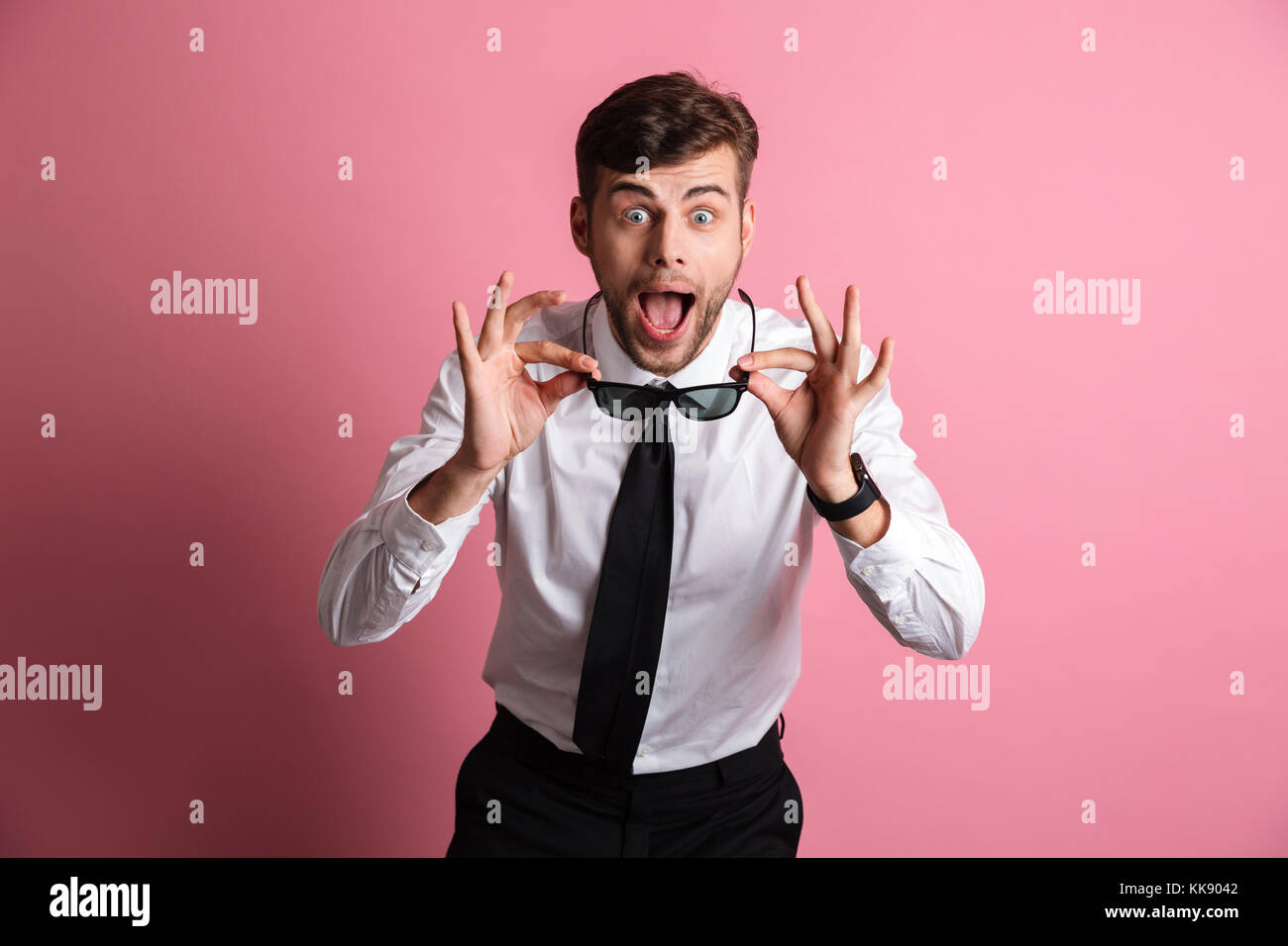 Portrait of a happy shocked man in white shirt holding sunglasses and ...