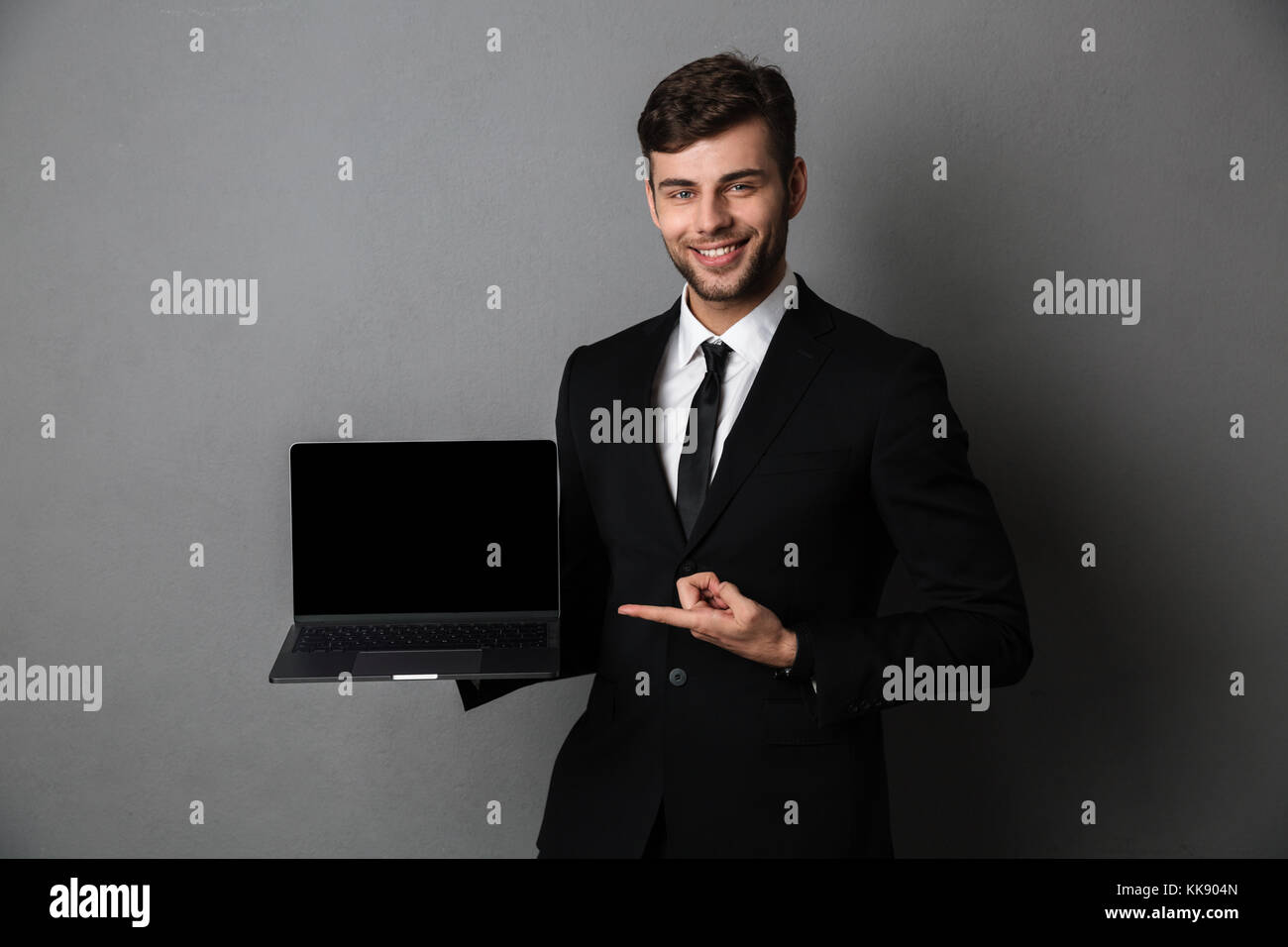 Image of cheerful young business man standing isolated over grey wall ...