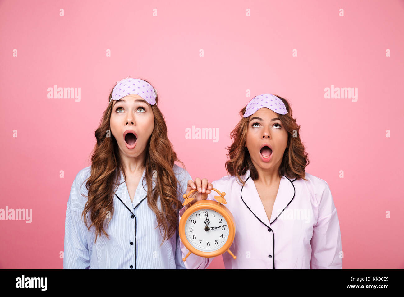 Image of two shocked friends women in pajamas isolated over pink ...