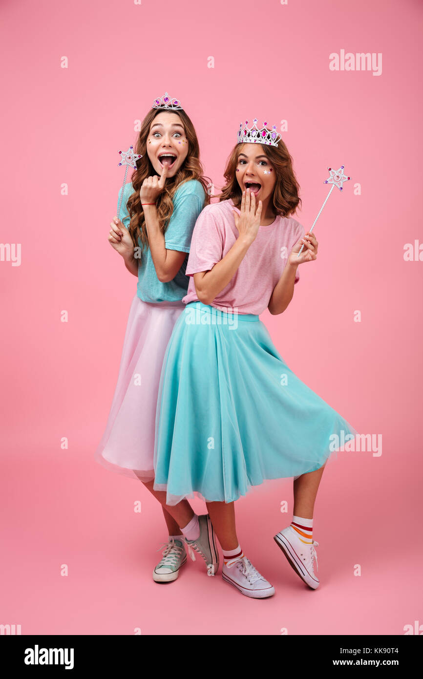 Full length of pretty young girls dressed in princess costumes holding ...