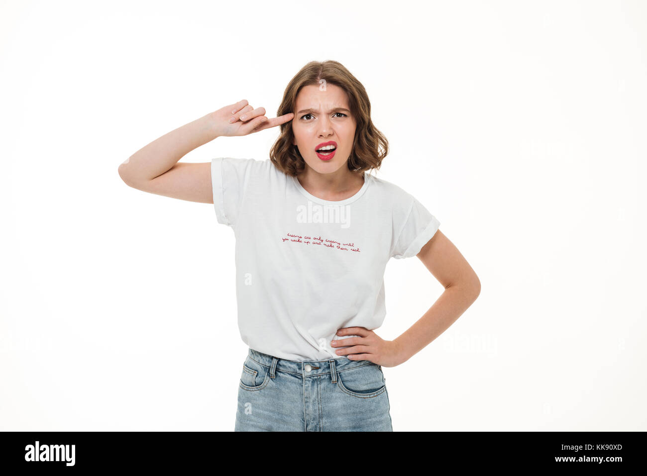 Portrait of a confused young girl pointing finger to her head and ...