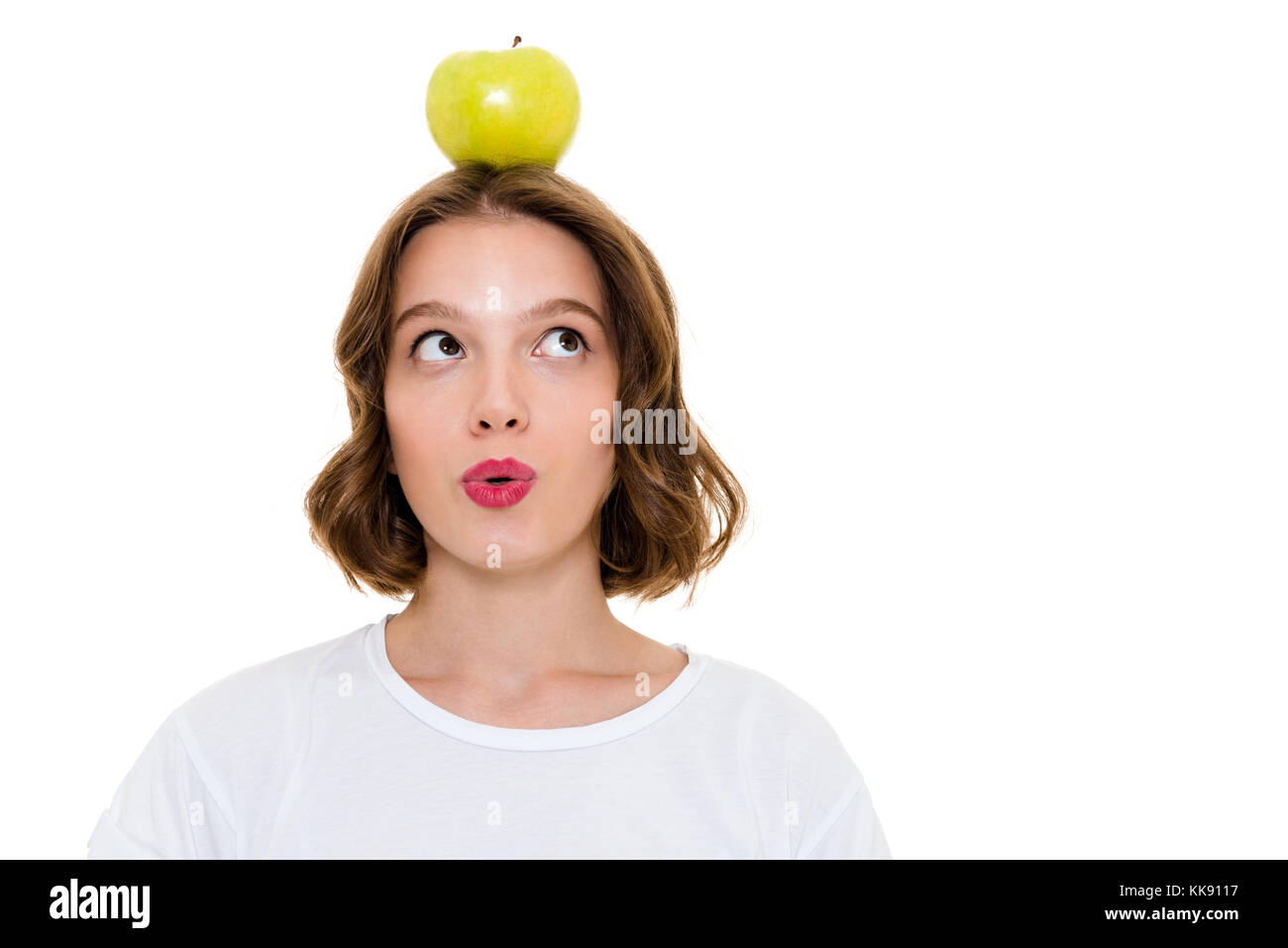 Image of thinking pretty caucasian woman holding apple on head standing ...