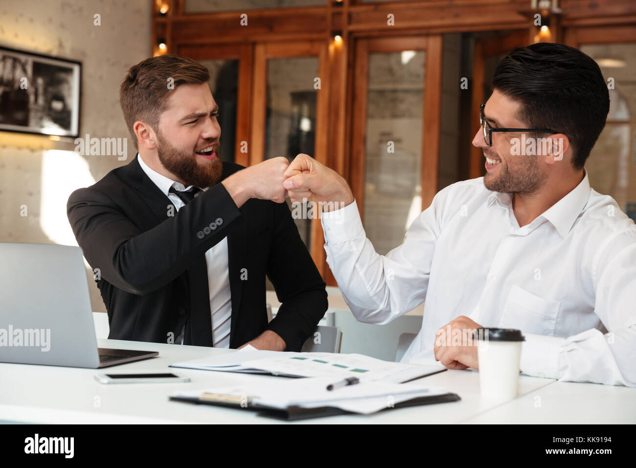 Two funny bearded colleagues in formalwear punched while sitting at ...