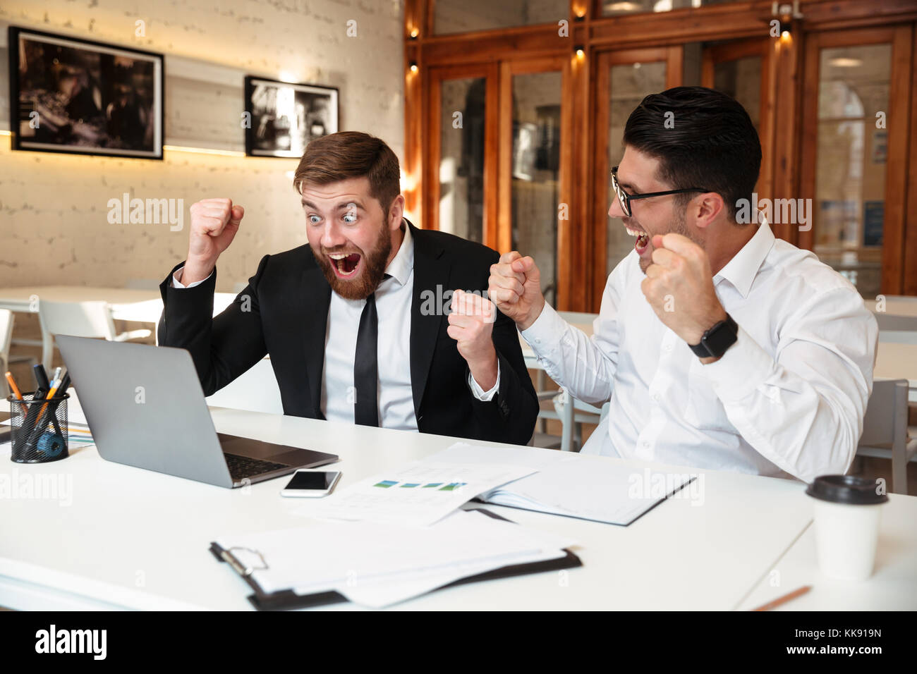 Two successful employees looking at a computer monitor on the table ...