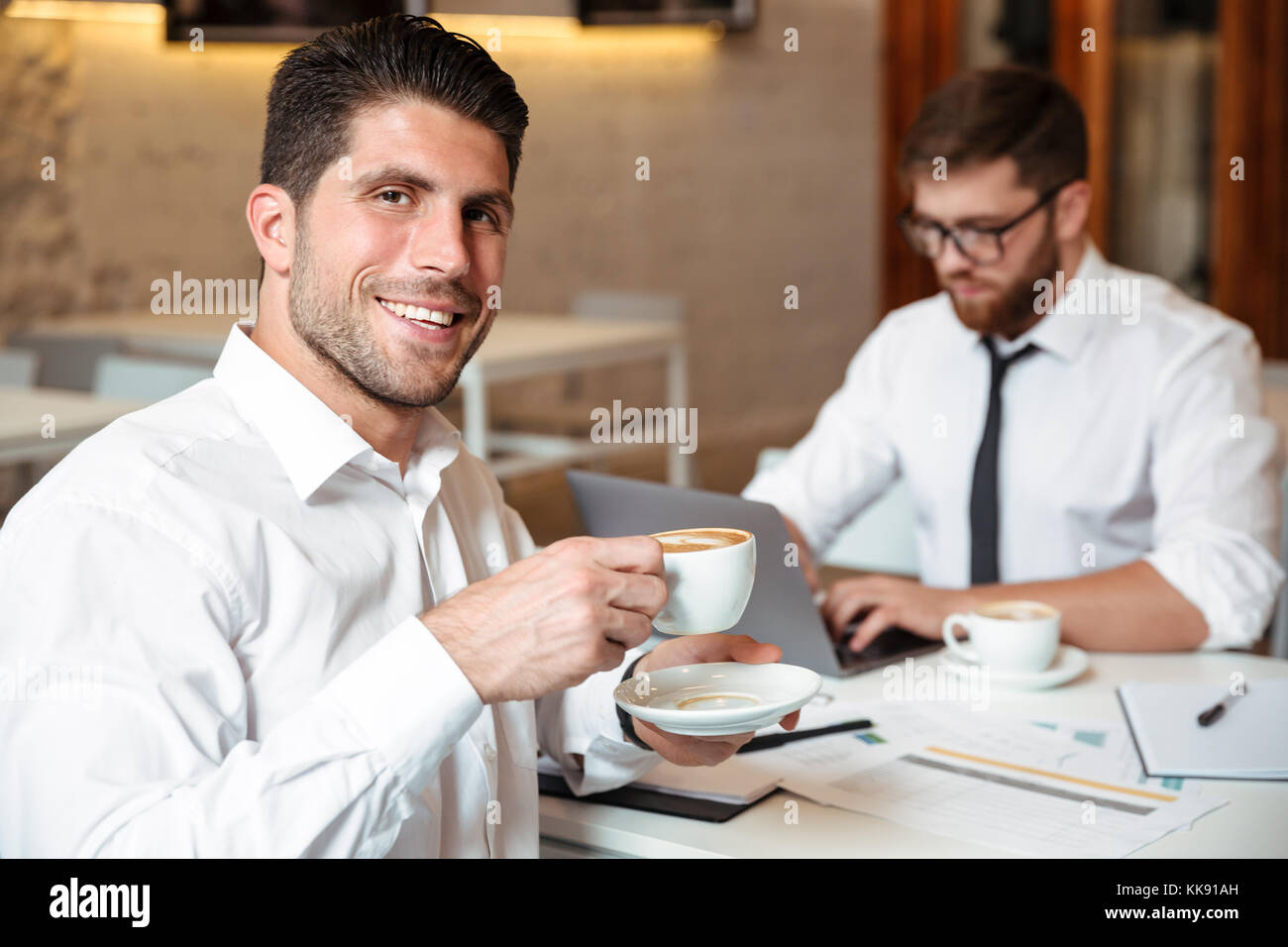 Portrait of a smiling handsome businessman drinking coffee with his ...