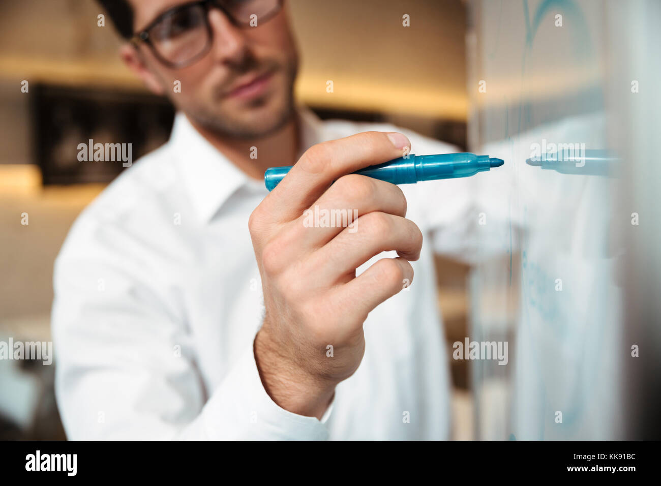 Close up portrait of a young businessman in eyeglasses writing on a ...