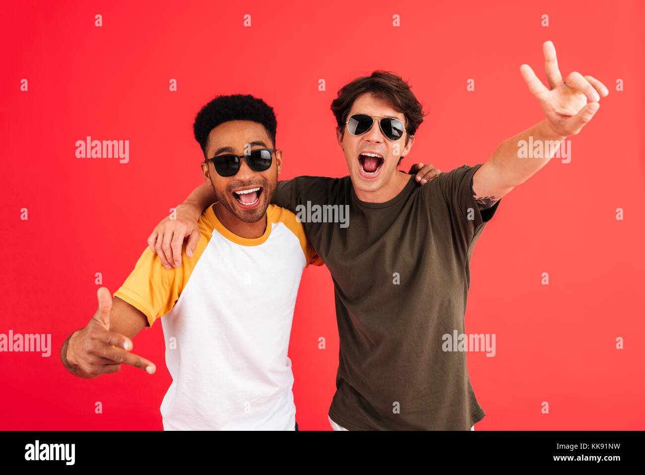 Two smiling cheerful men in sunglasses posing while standing and ...