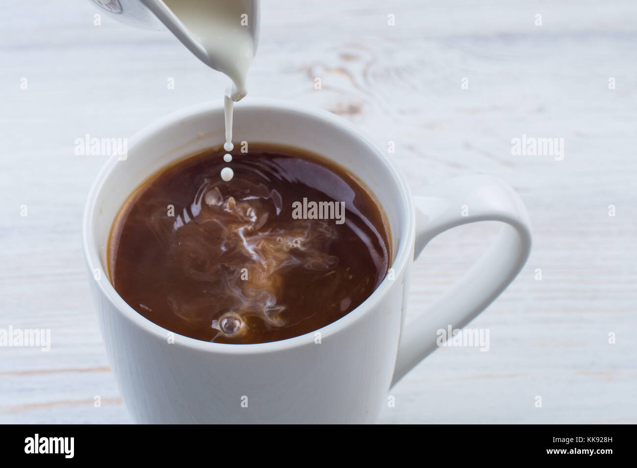 Adding milk to a cup of coffee Stock Photo - Alamy