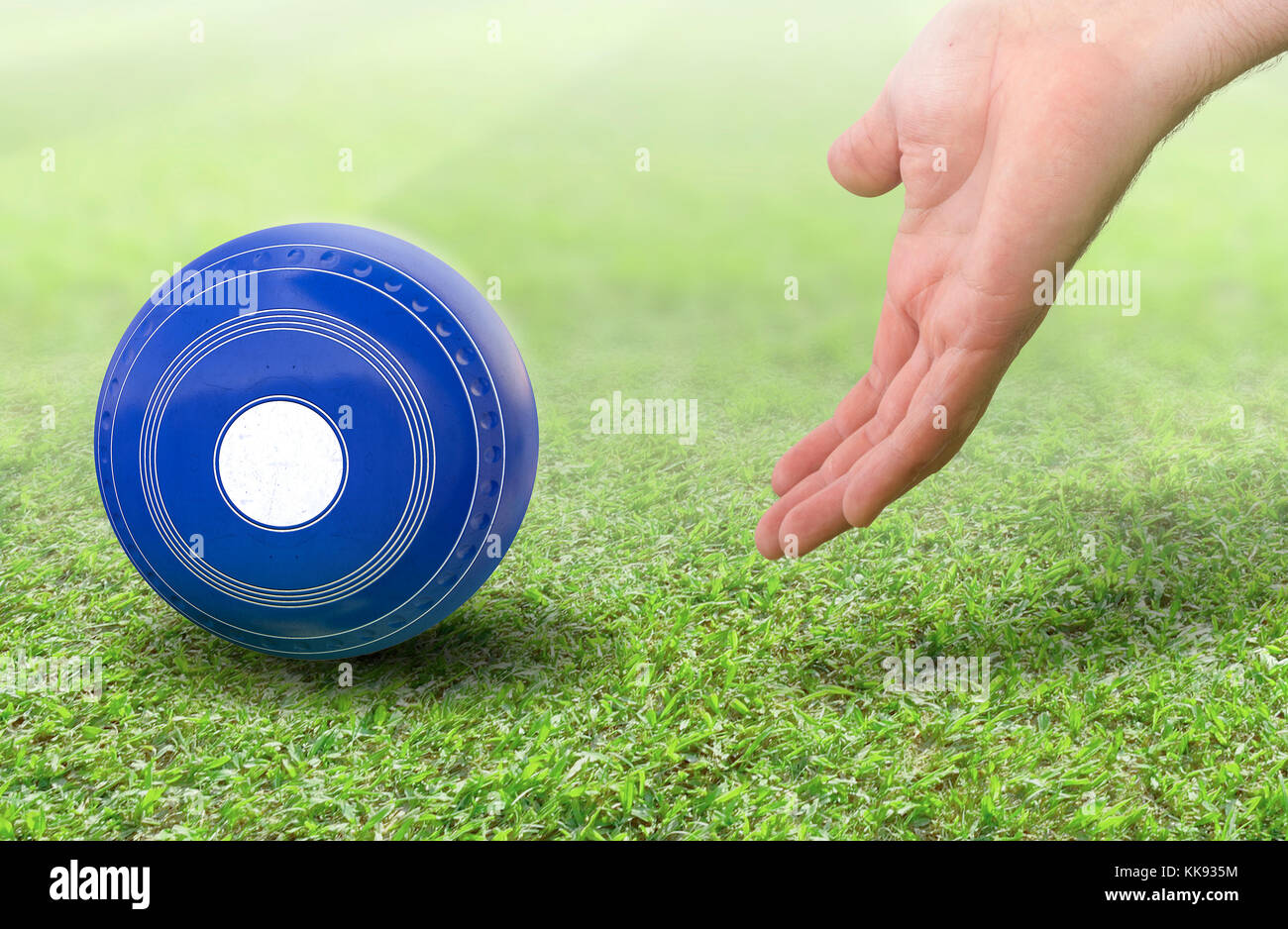 A male hand bowling and releasing a blue wooden lawn bowling ball on a ...