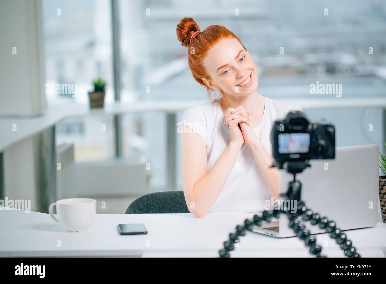 Young woman recording video on camera mounted on tripod for her vlog ...