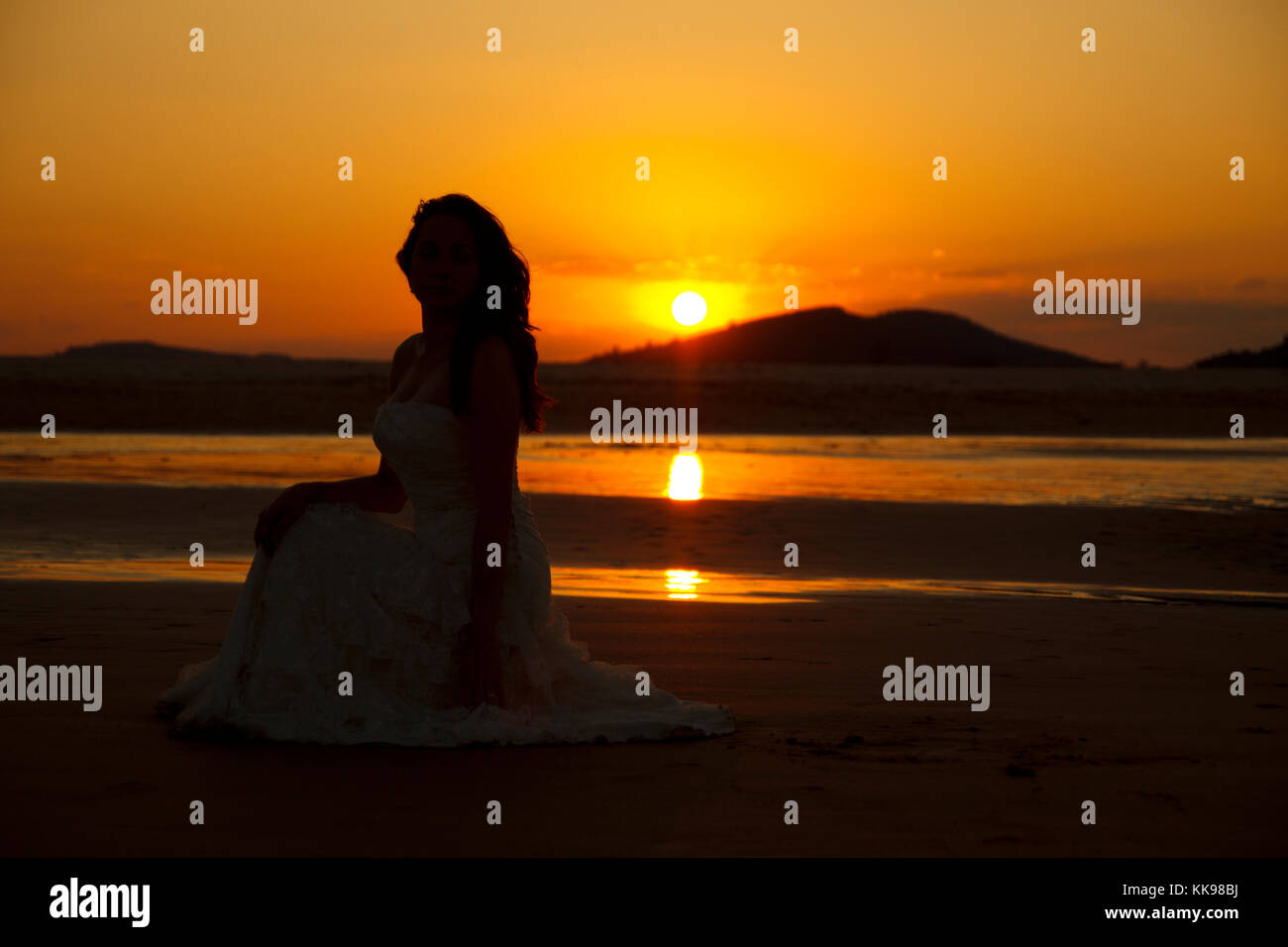 Bride contemplating beach at sunset. Low light Stock Photo - Alamy