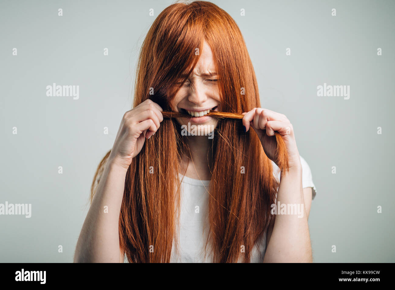 Sad redhead girl bite her damaged hair Stock Photo - Alamy