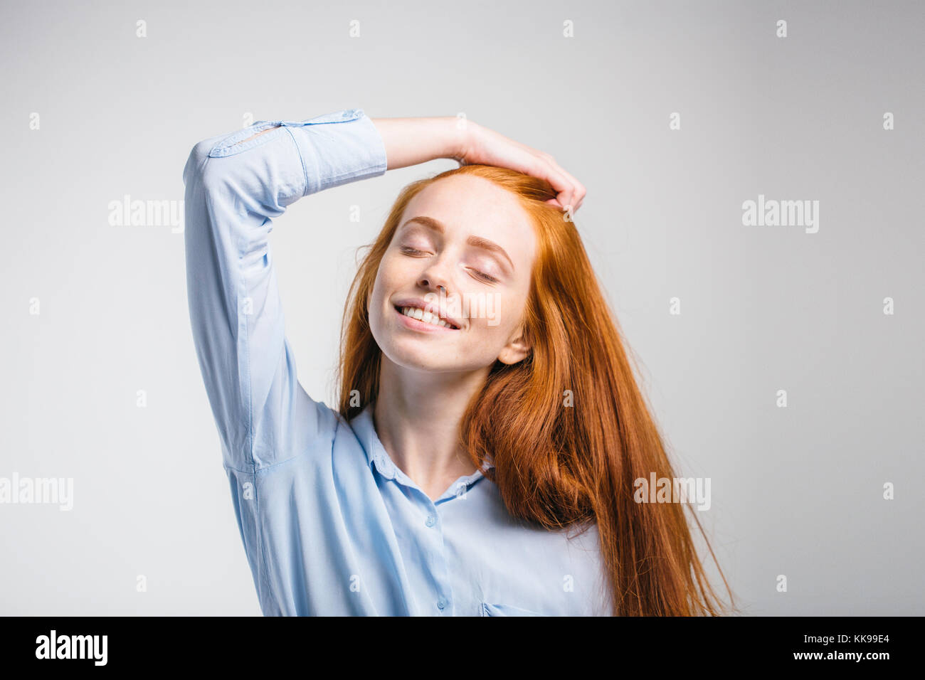 Happy beautiful girl smiling with closed eyes touching her red hair Stock Photo - Alamy