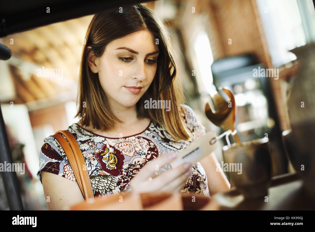 Young woman in a shop, looking at a price tag. | usage worldwide ...