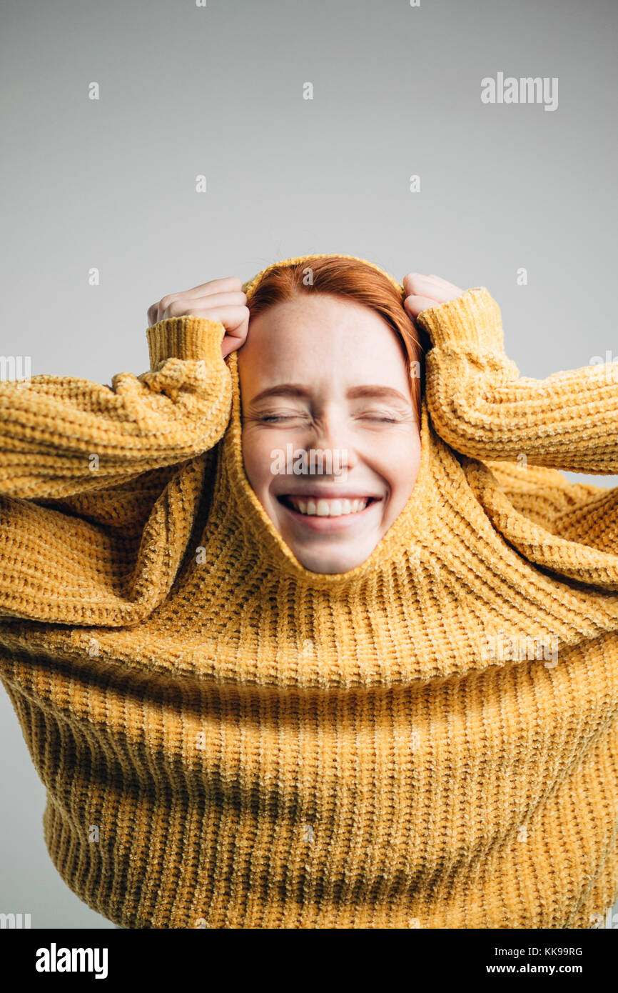 Fashion young woman pulling yellow sweater and having fun over white ...