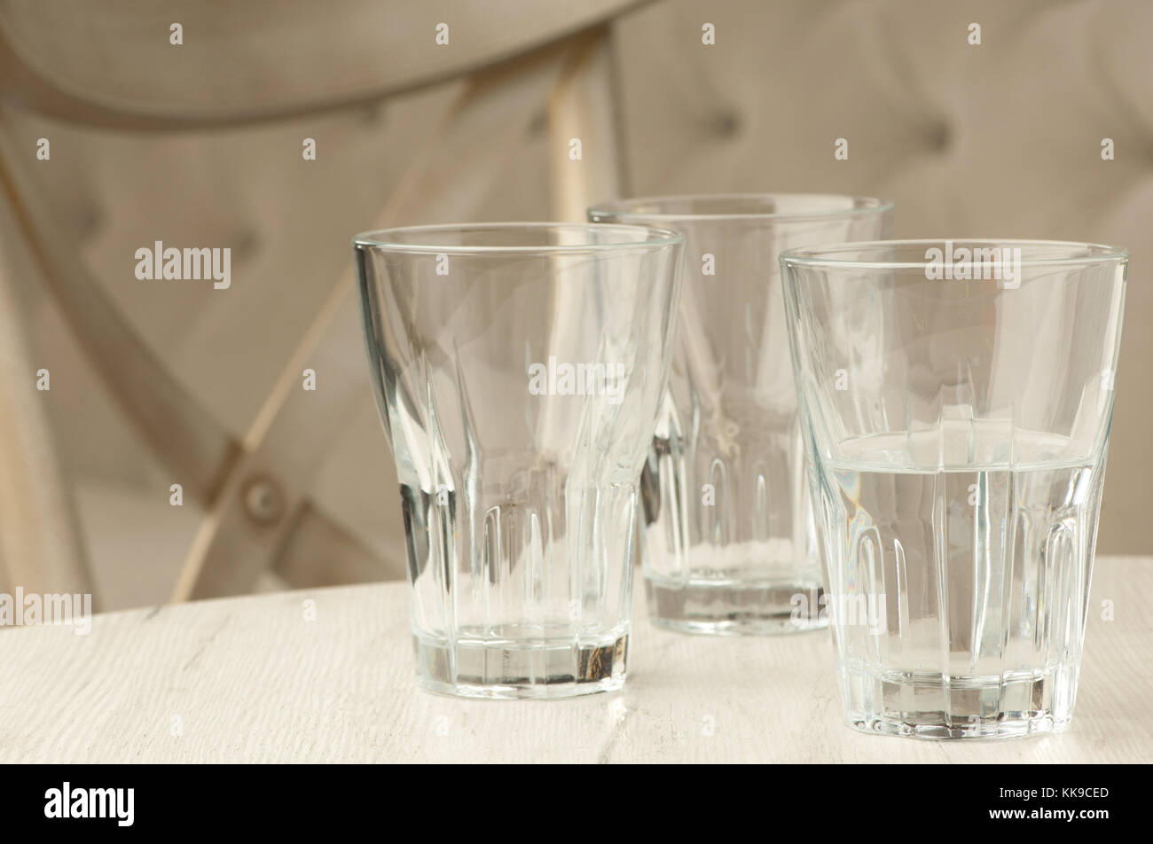Three empty glass transparent cup on the table against the background ...