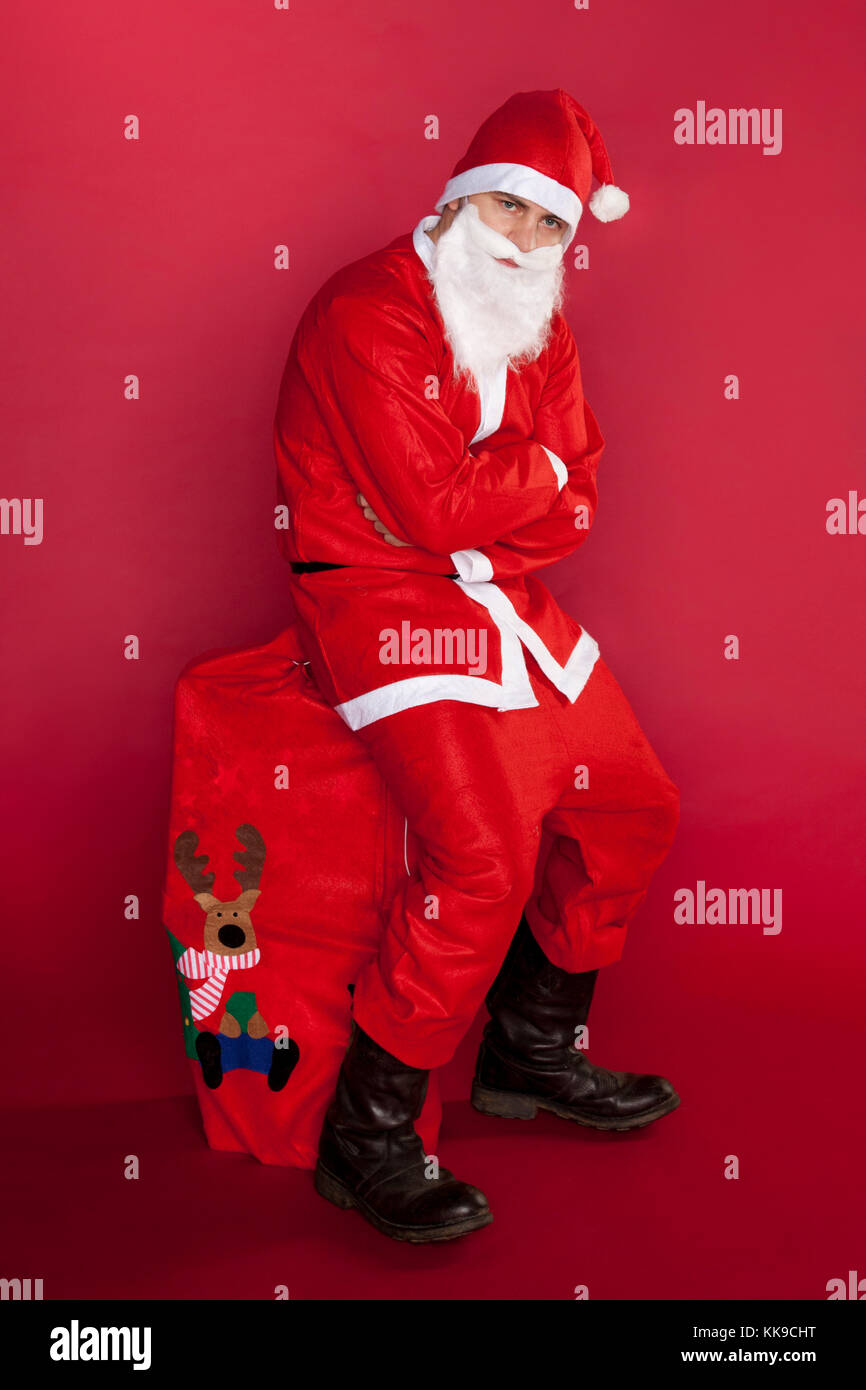 Unhappy Santa Claus is sitting on a big bag stuffed with presents Stock ...