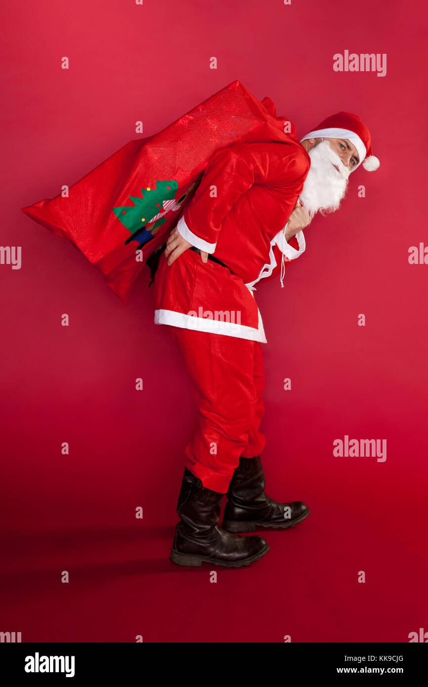 Santa Claus has back pain from the weight of gifts Stock Photo - Alamy