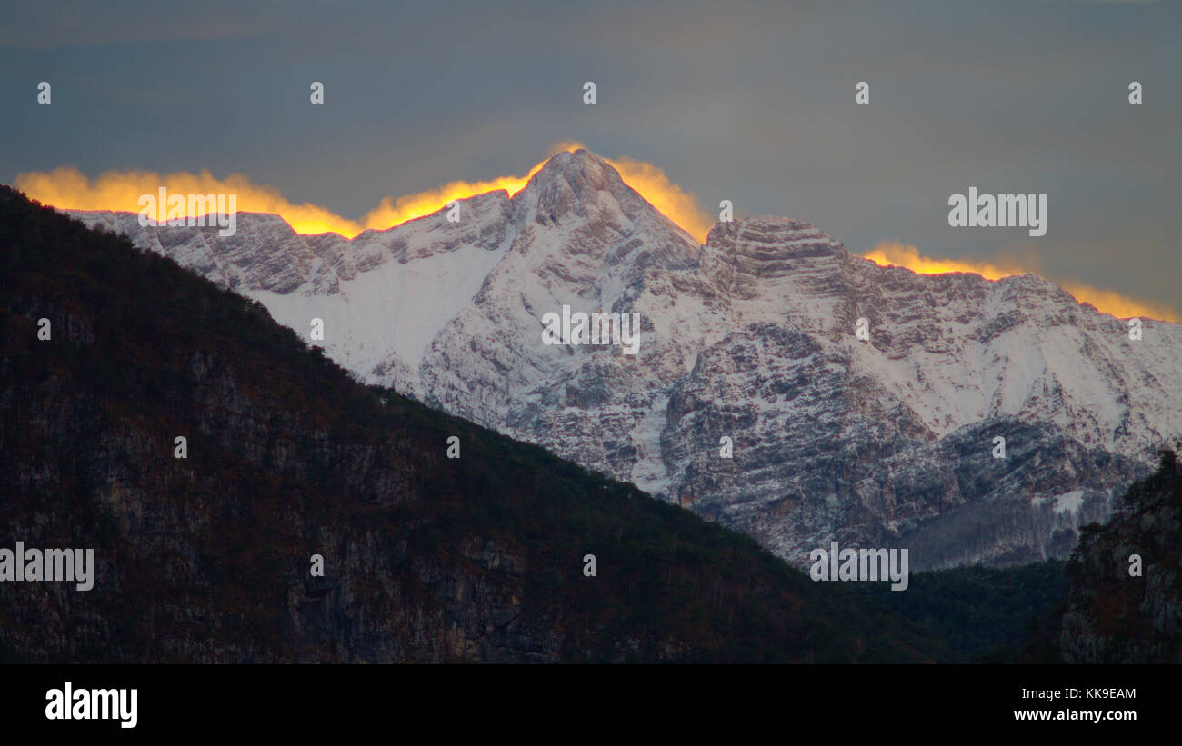 Snow powder raised in the sky by strong wind and lit by orange color ...