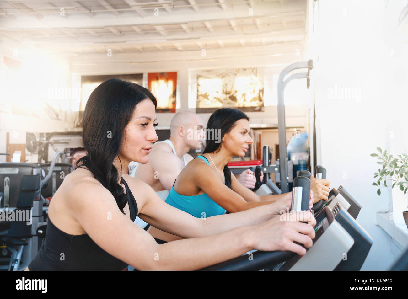 Group of three people in the gym, exercising their legs doing cardio ...