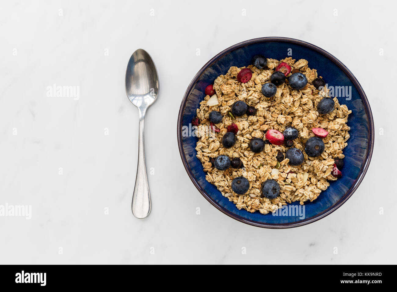 Breakfast fruit cereal bowl with silver spoon on white marble ...