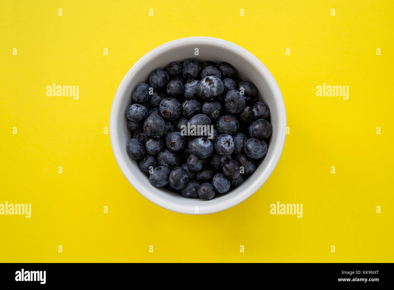 Bowl of blueberries on bright yellow background Stock Photo - Alamy