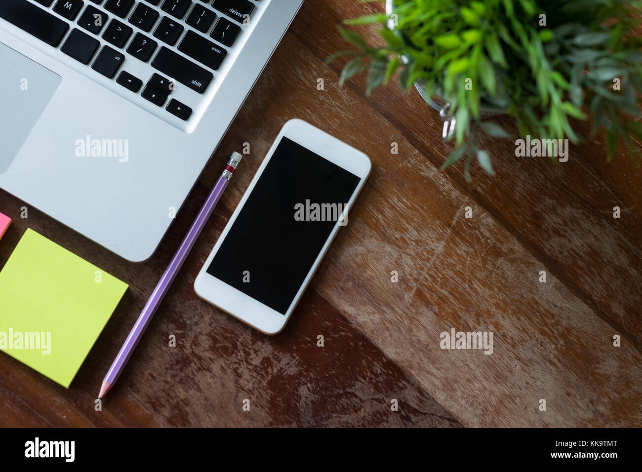 top view of office desk table with laptop, phone, flower and yellow ...