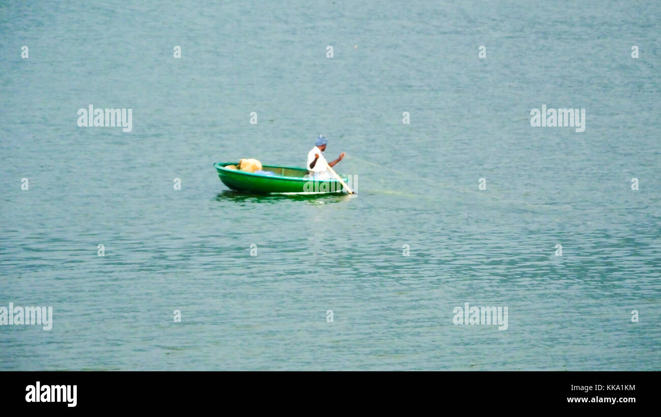 Man sailing a small round boat in the water reservoir to catch fish in ...