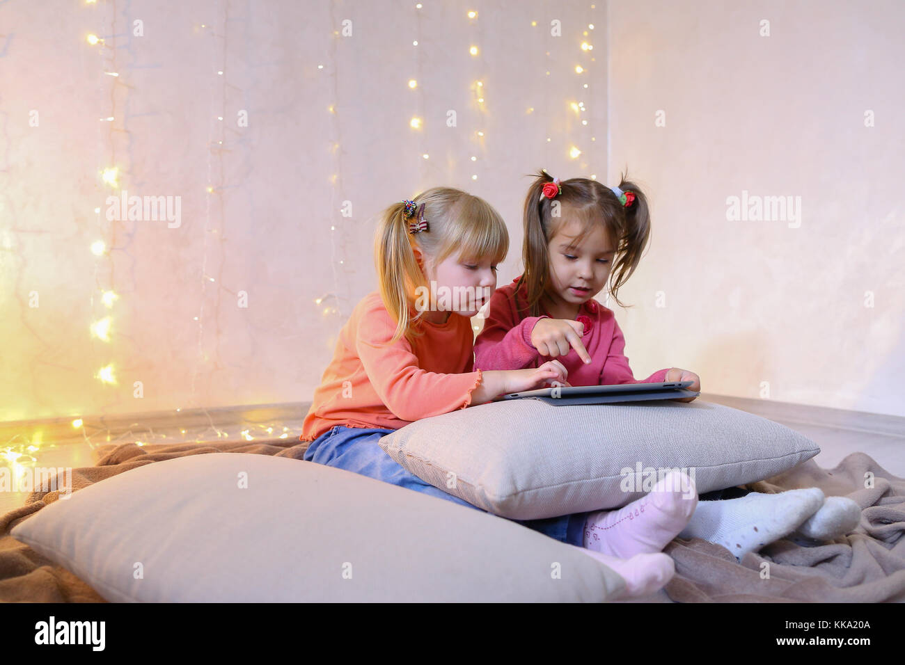 Little girls involved in use of tablet and sit on floor in brigh Stock ...