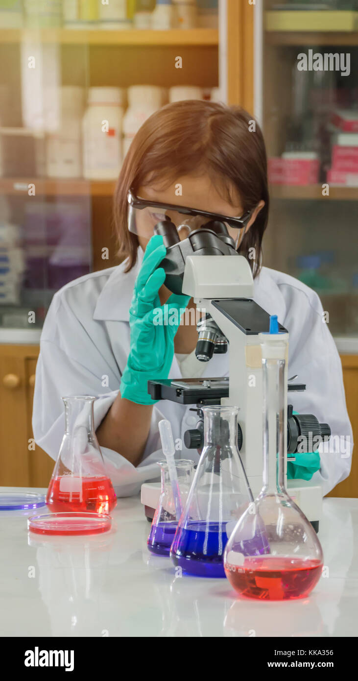 asian little scientist looking through a microscope in a laboratory ...
