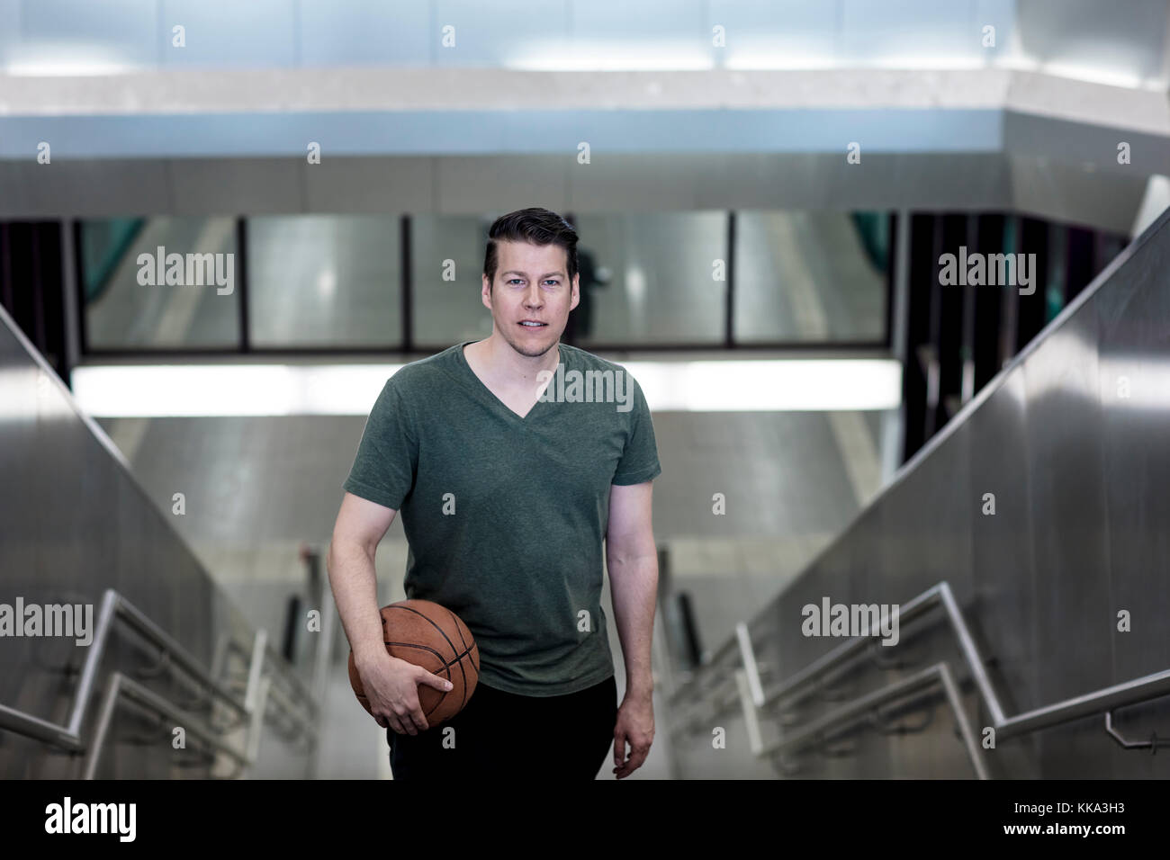 A man with a basketball in his hands looking at the camera with a ...