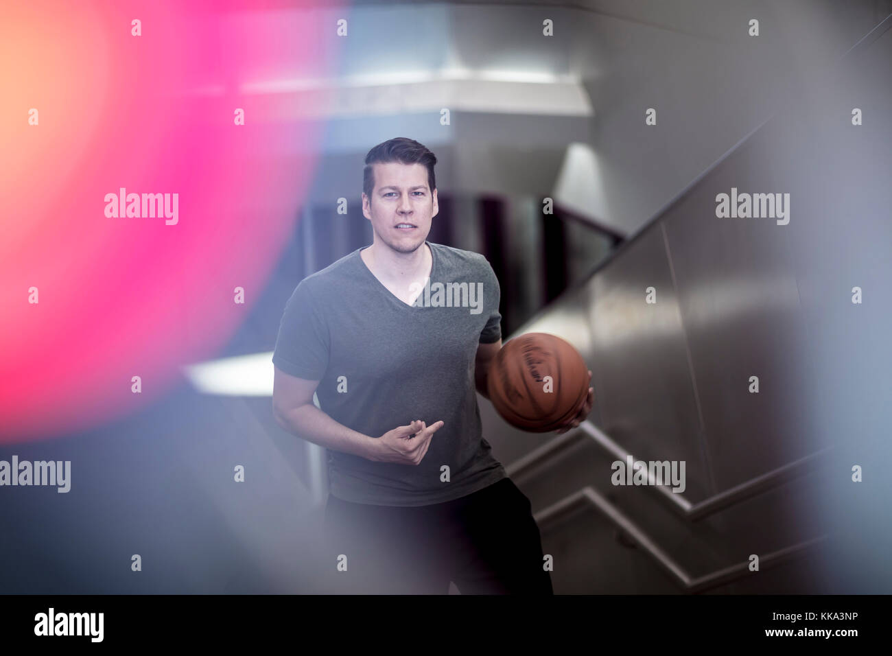 A man walking up a stairwell with a basketball in hand. Lens flare ...