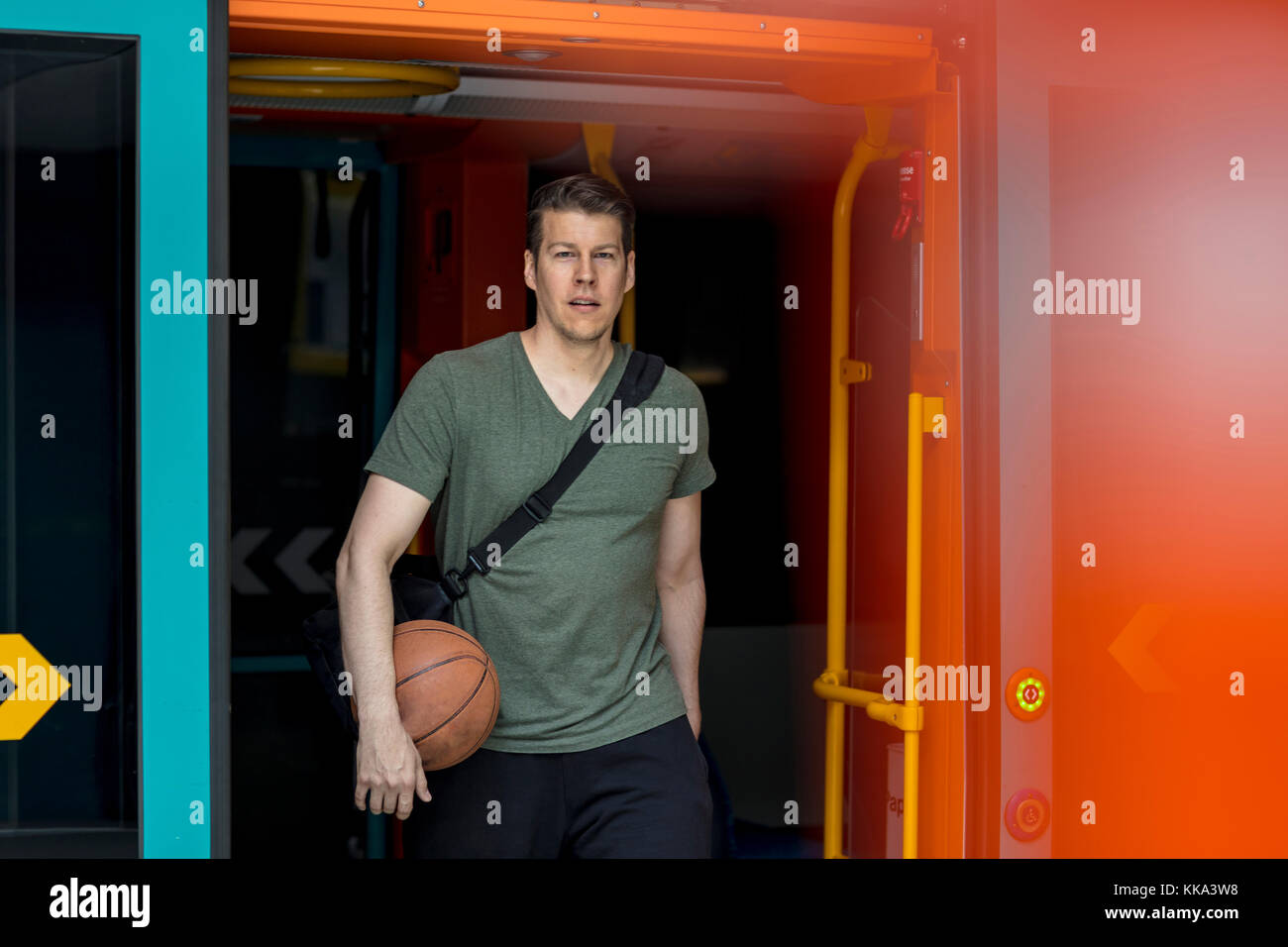 Athletic man with a basketball in hand walking out of a subway train in ...