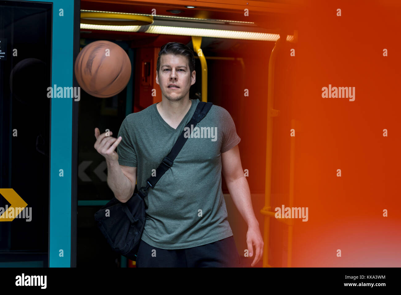 Athletic man with a basketball in hand walking out of a subway train in ...