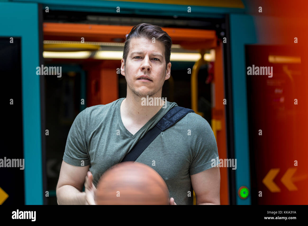 Athletic man with a basketball in hand walking out of a subway train in ...