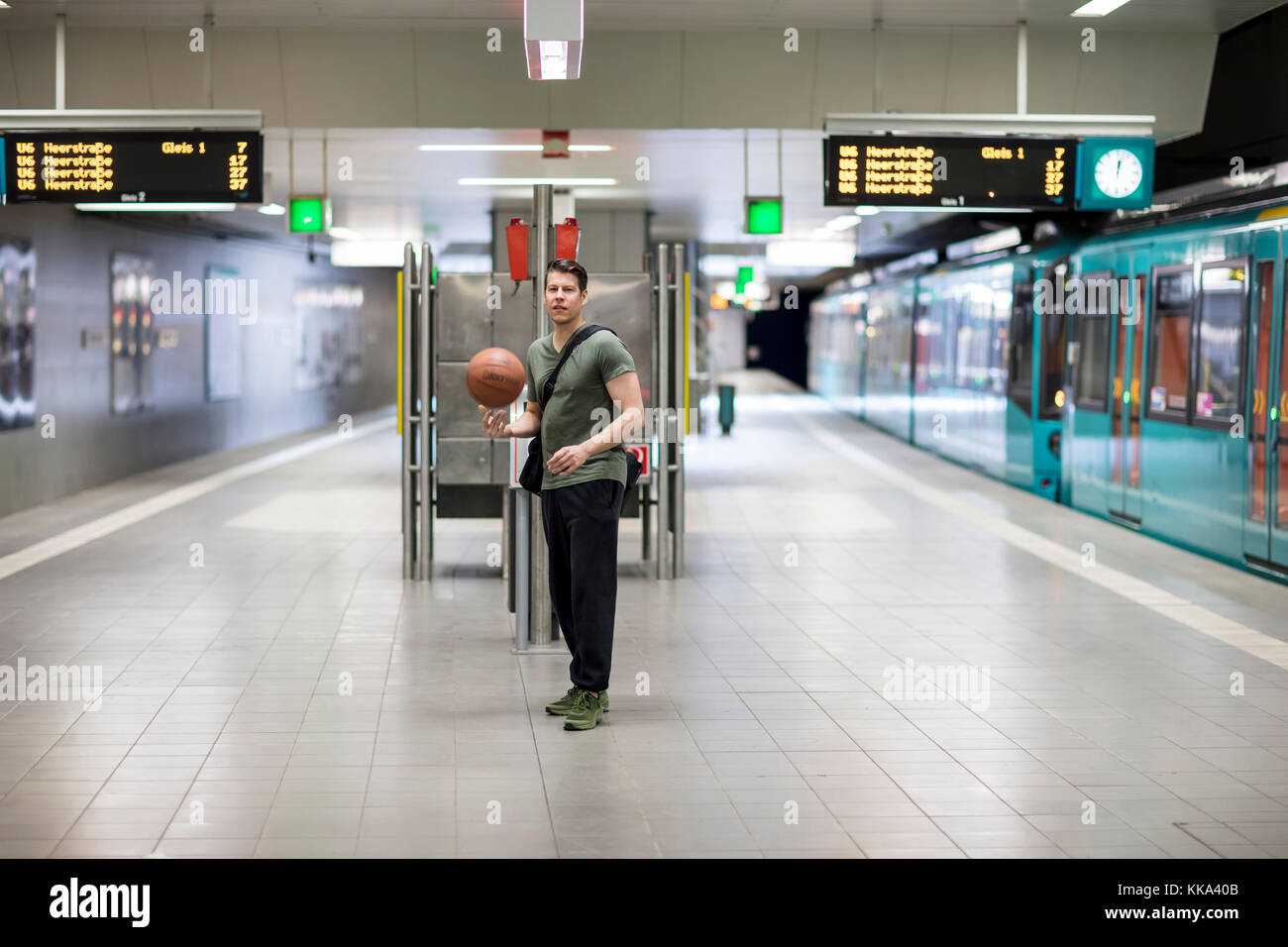 A man with a basketball and dressed in activewear standing at a subway ...