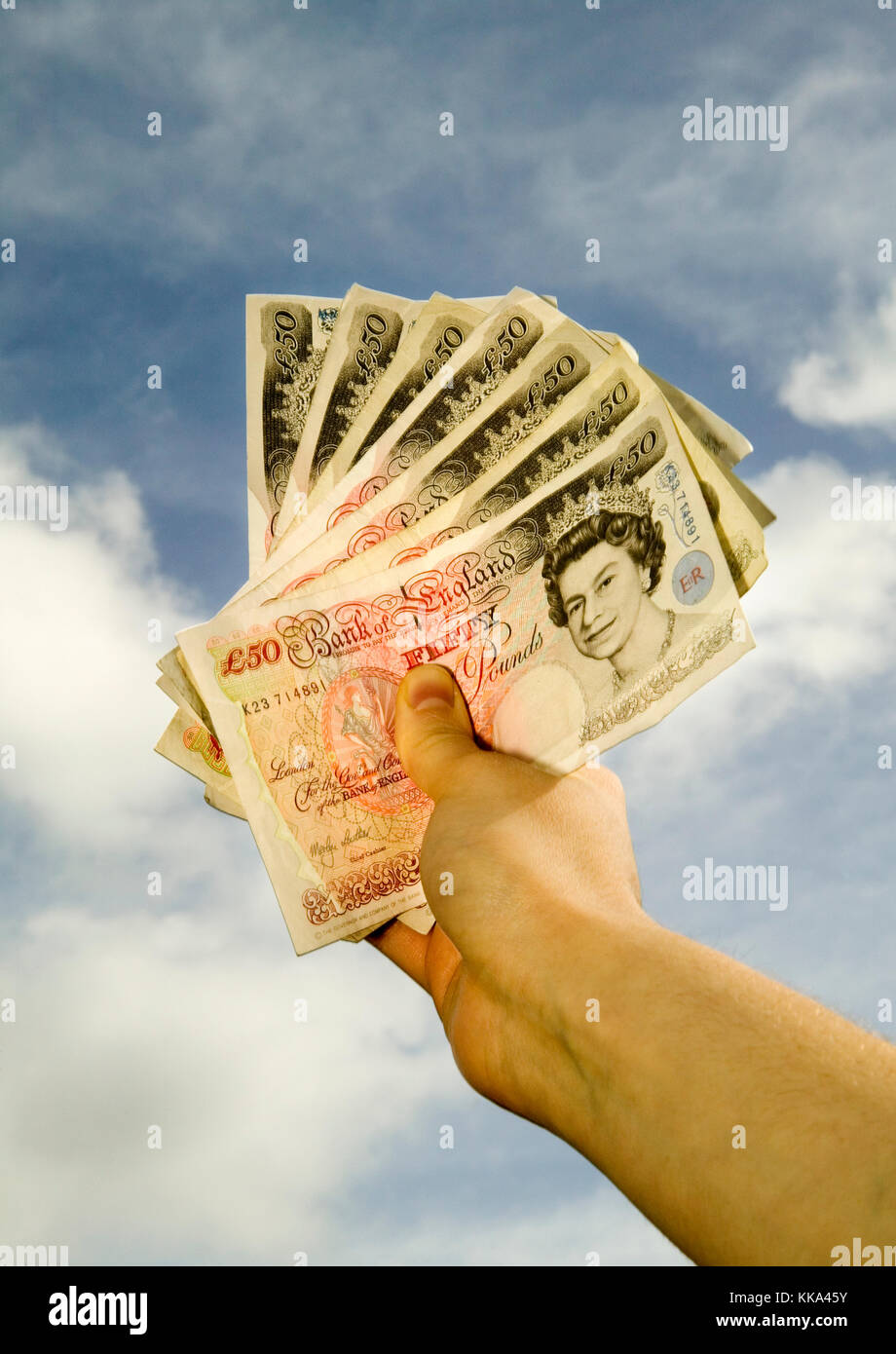 Hand holding stack of cash high up in the air Stock Photo - Alamy