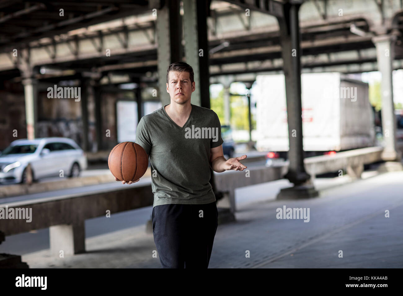 Man with a basketball standing under a city bridge Stock Photo - Alamy