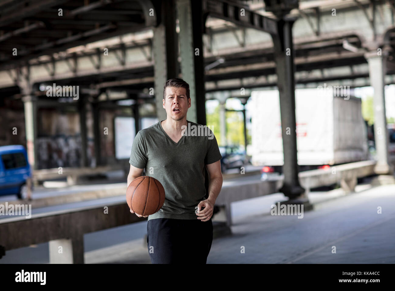 Man with a basketball standing under a city bridge Stock Photo - Alamy