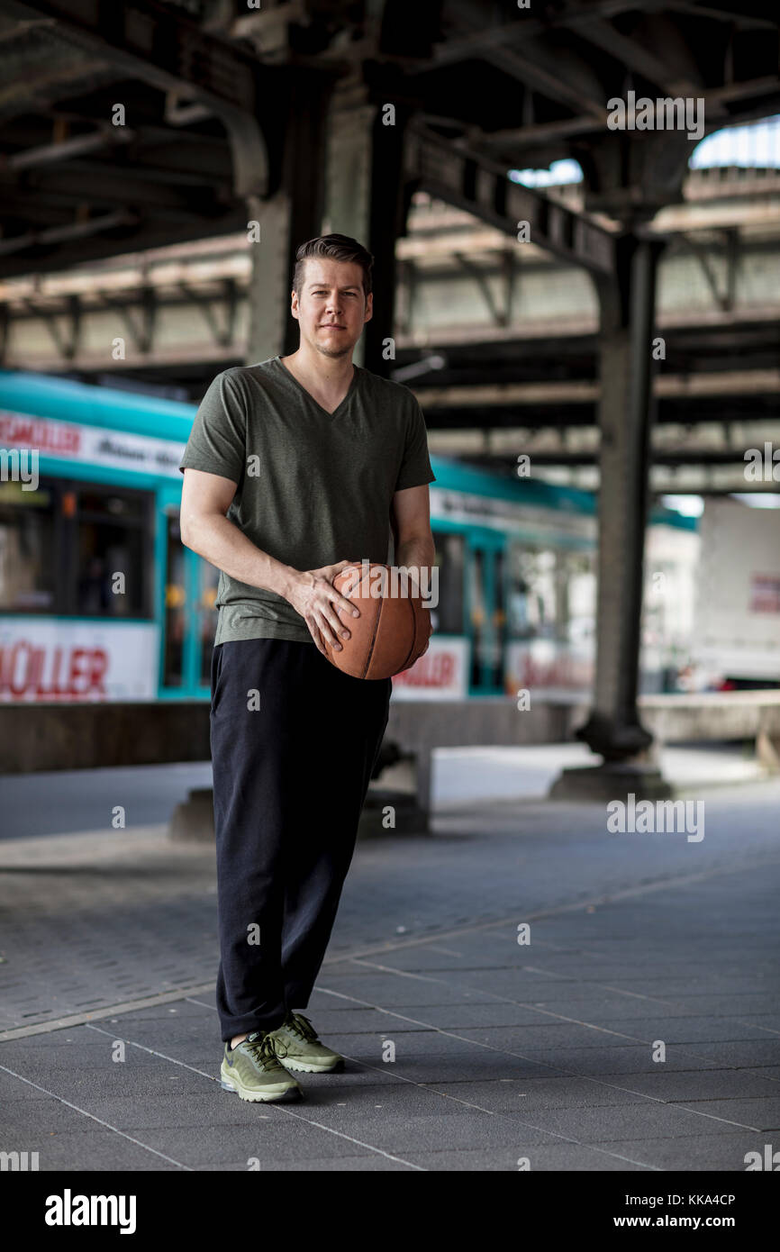 Man with a basketball standing under a city bridge Stock Photo - Alamy