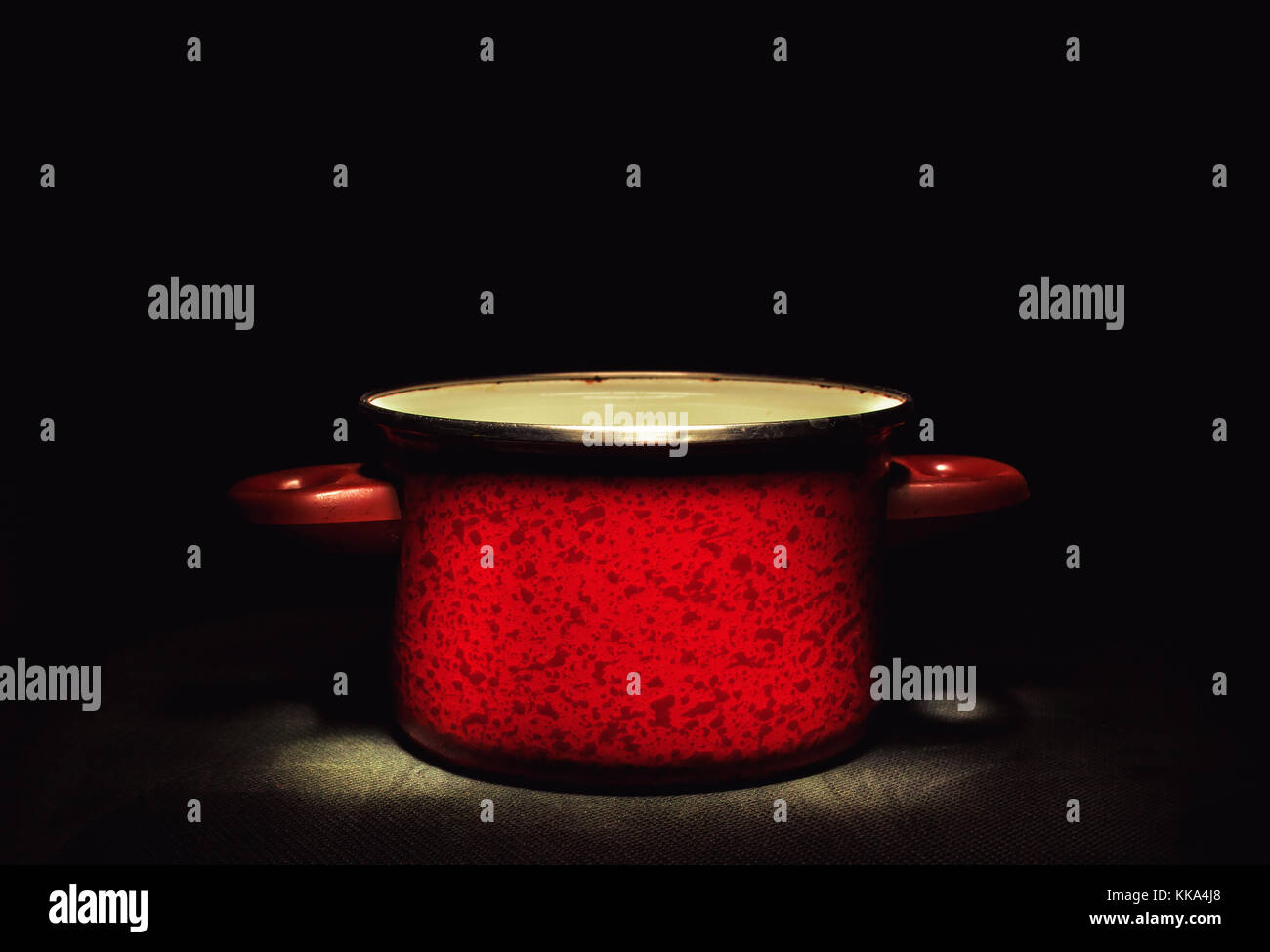 One old red cooking pot in the dark, accentuated shape and texture ...